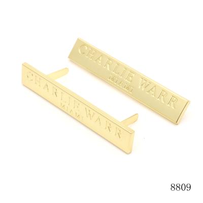 China Custom embossed zinc alloy metal logo plate gold rectangular bag name label with back prongs for leather handbag hardware for sale