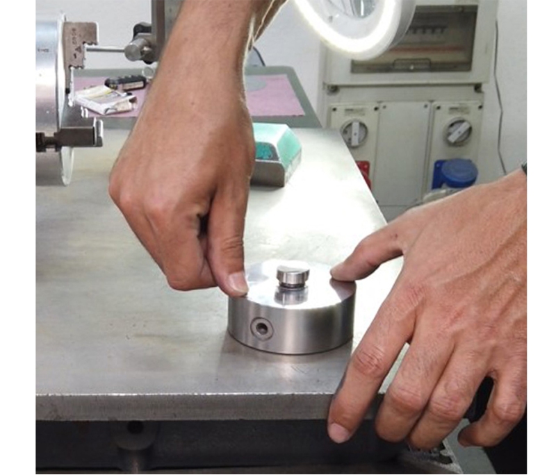Checking the flatness of a load cell: the load cell is placed on a perfectly flat surface and the operator exerts a force on it with their fingers. Checking the flatness of a load cell: the load cell is placed on a perfectly flat surface and the operator exerts a force on it with their fingers.