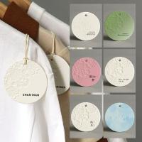 China Embossed Round Paper Hang Tags With Relief Floral Pattern For Apparel Branding for sale
