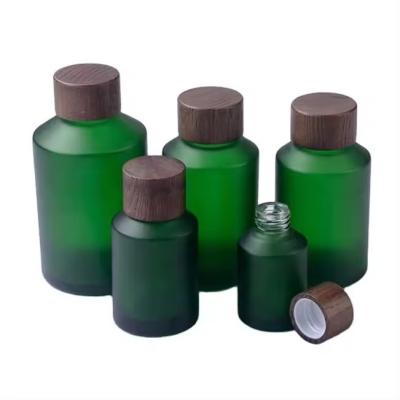 China 30g,50g,15ml,30ml,60ml,120ml, Green Frosted Glass Bottle With Wooden Screw Lid for sale