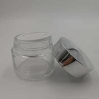 China MSDS Clear 100g Glass Cream Jar With Shiny Silver Cap White Lid Mask Mud for sale