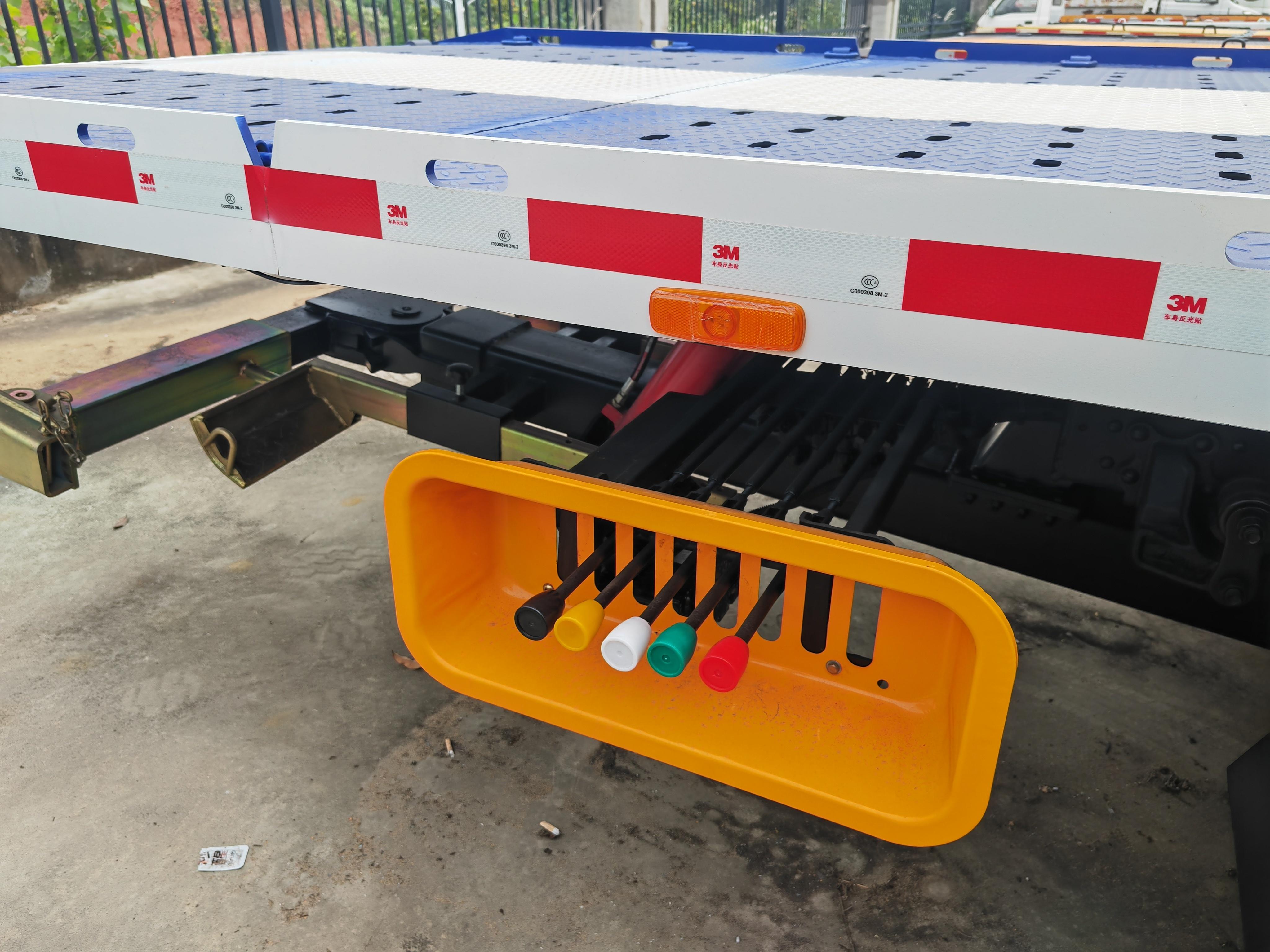 Close-up of hydraulic multi-way control valves with yellow safety guard on a CLW Group flatbed wrecker.