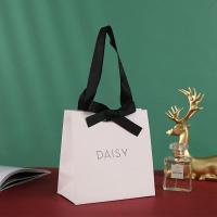 China Embossing Ribbon Handle Cosmetic Paper Bags White Paper Carrier Bags for sale