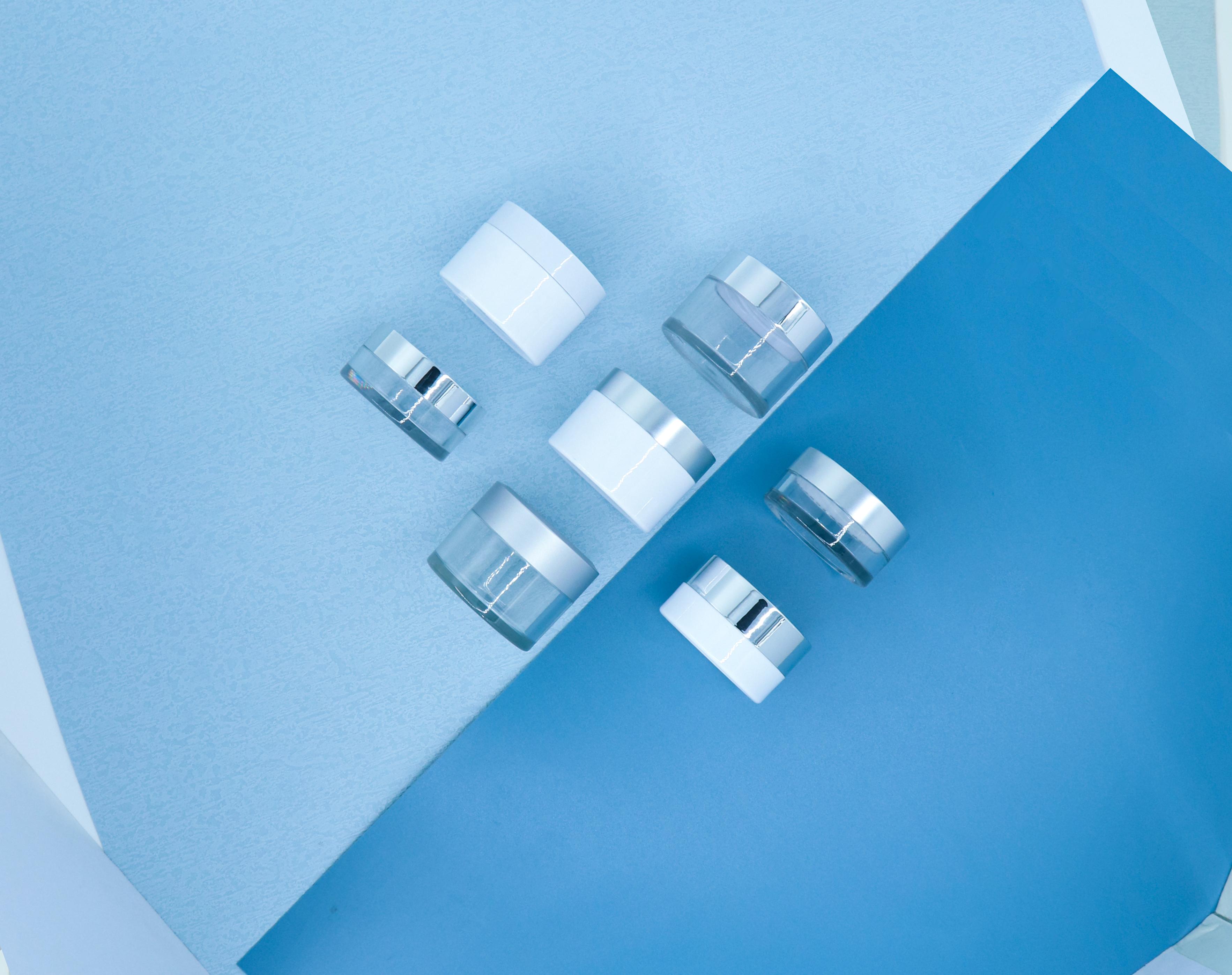 Cosmetic cream jars in eight different styles displayed diagonally on blue background