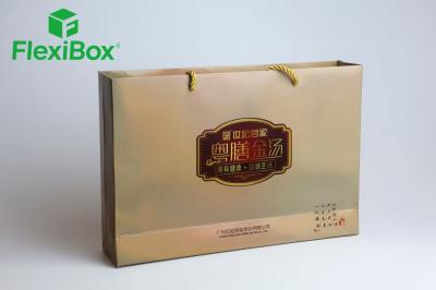 China Premium Champagne Gold Specialty Paper Gift Tote Bag with Red-and-Gold Foil-Stamped Emblem and Yellow Cord Handles for sale