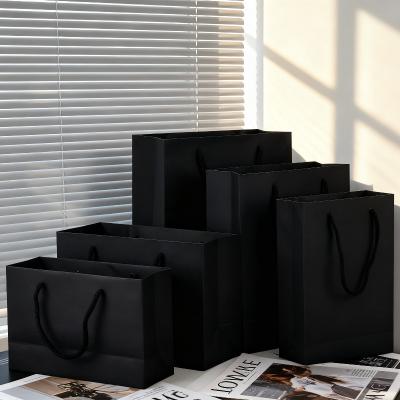 China Black Cardboard Bag Custom Paper Tote Packaging Bag Black Kraft Paper Bag Clothing Store Tote Bag for sale