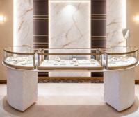 China Luxury Modern Curved Jewelry Display Island with Gold Metal Frame LED Lighting Quilted White Base for Mall Use for sale