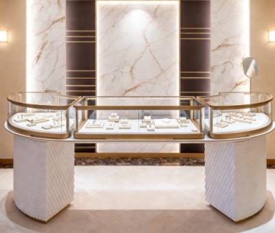 China Luxury Modern Curved Jewelry Display Island with Gold Metal Frame LED Lighting Quilted White Base for Mall Use for sale
