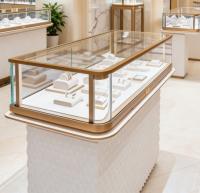 China Luxury Modern Curved Jewelry Display Island with Gold Metal Frame LED Lighting Quilted White Base for Mall Use for sale