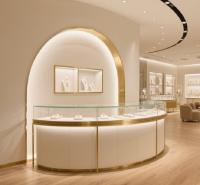 China Luxury Curved Island Jewelry Display Counter for Mall Use | Cream Body Gold Trim | Glass Showcase LED Lighting | Customizable for sale