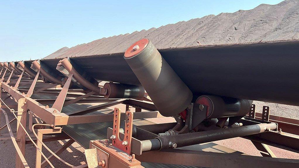 Conveyor belt running centered on troughing idlers at a mining site