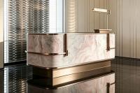 China Luxury Pink Onyx Marble Reception Desk with Bronze Metal Trim and Curved Design for Salon Front Counter for sale