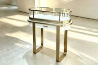 China Custom Luxury Oval Curved Glass Jewelry Display Table with Brushed Gold Metal Leg and Lockable Storage Drawer for sale