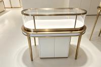 China Oval Curved Glass Jewelry Display Table with Slim Brushed Gold Metal Legs and Built-in LED Lighting for sale