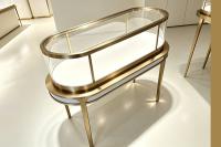 China Oval Curved Glass Jewelry Display Table with Slim Brushed Gold Metal Legs and Built-in LED Lighting for sale