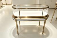 China Oval Curved Glass Jewelry Display Table with Slim Brushed Gold Metal Legs and Built-in LED Lighting for sale