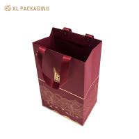 China Premium Matte Burgundy Wine Paper Gift Bag with Oriental Gold Foil Stamping and Rivet Reinforced Satin Ribbon Handles for sale