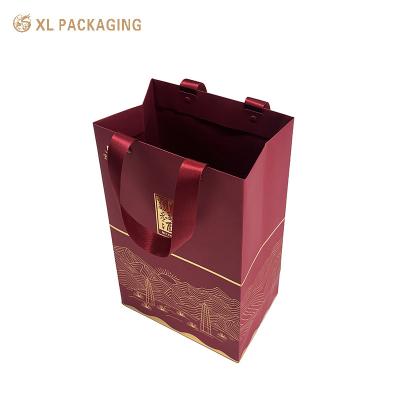 China Premium Matte Burgundy Wine Paper Gift Bag with Oriental Gold Foil Stamping and Rivet Reinforced Satin Ribbon Handles for sale