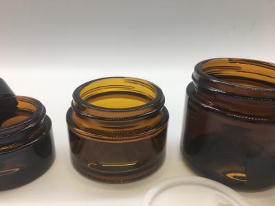 China Transparent Cosmetic Refill Amber Glass Jar Straight Round Shape With Plastic Black Lid for sale